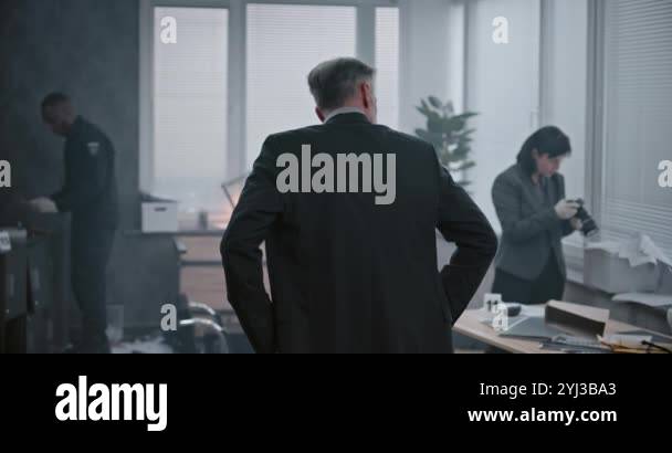 Office robbery case: Back view of male detective examining crime scene ...