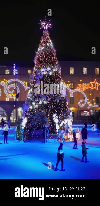People enjoy Christmas evening skating on a festive ice rink around a ...