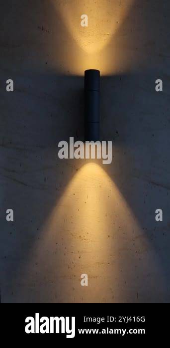 spot wall light illuminates the wall of facade of house in a conical ...