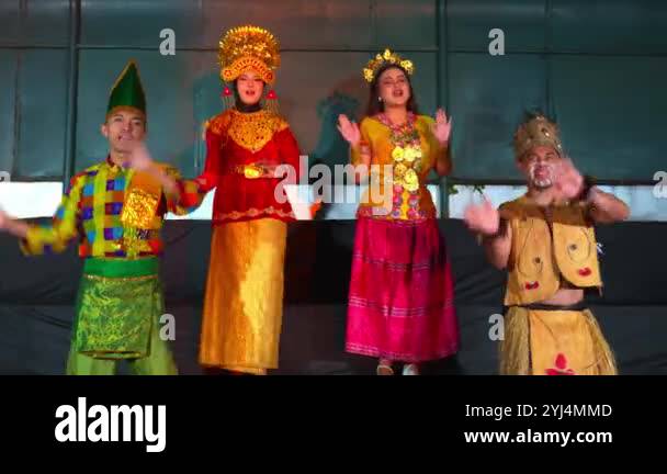 Four people dressed in traditional Filipino costumes performing a ...
