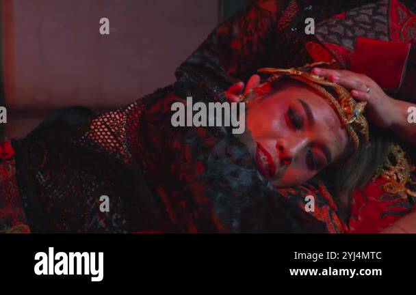 A person in traditional attire with intricate headgear, lying down and ...