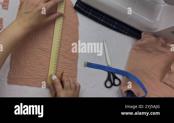 Seamstresss hands draw straight line on piece of fabric with ruler and ...