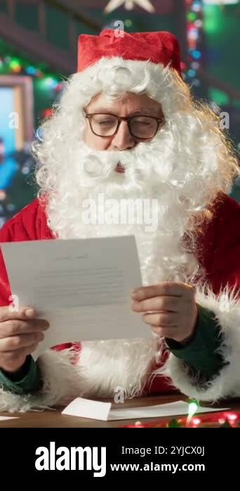 Vertical Video Portrait of cheerful Father Christmas reading letters by ...