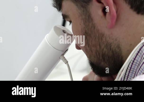 Patient in ophthalmology clinic. Man looks inside apparatus for ...