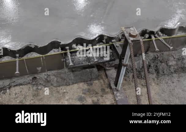 A detailed view shows a concrete slab being carefully finished with ...
