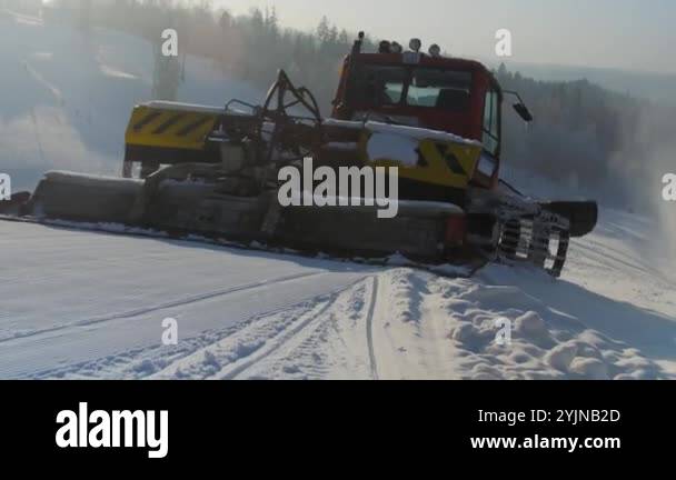 Snow Grooming Tractor Starts Down the Hill Preparing the Ski Slope. A ...