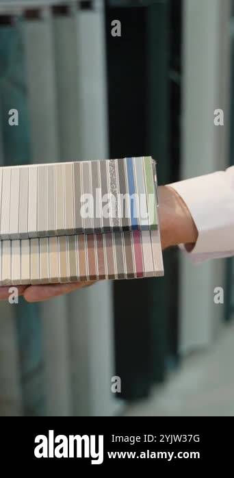 A knowledgeable tile sales consultant stands in a showroom holding a ...