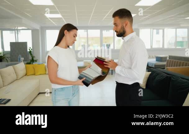 A customer and consultant review fabric options, carefully considering ... A customer and consultant review fabric options, carefully considering ...