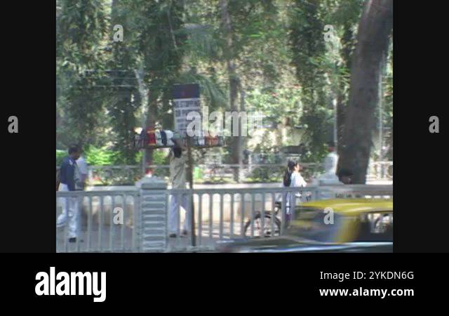 MUMBAI - 1999 - A dabbawala carries a tray of food alongside a busy ...