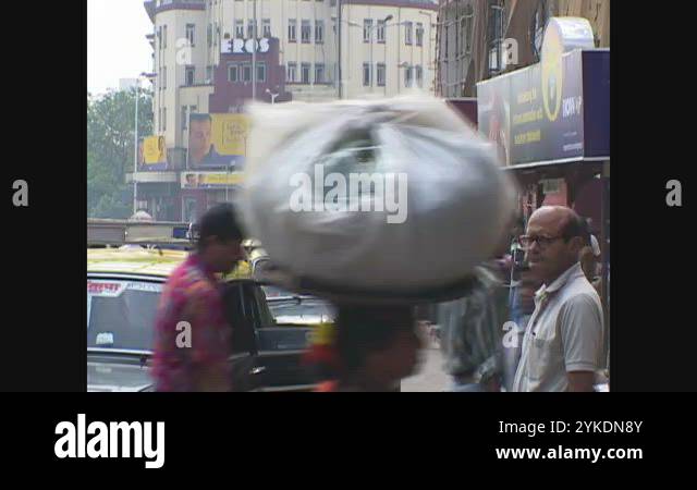 MUMBAI - 1999 - People walk by a line of cars on a busy street in ...
