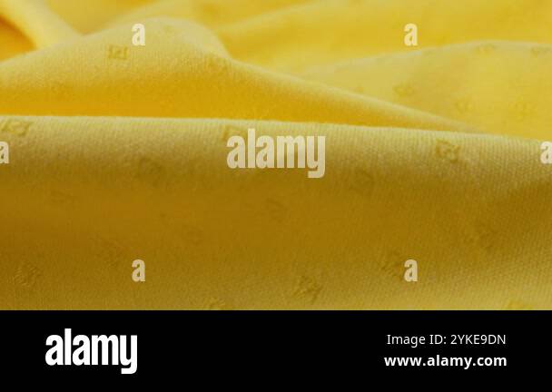 Close-up view of the soft folds of the tan yellow cotton fabric. The ...