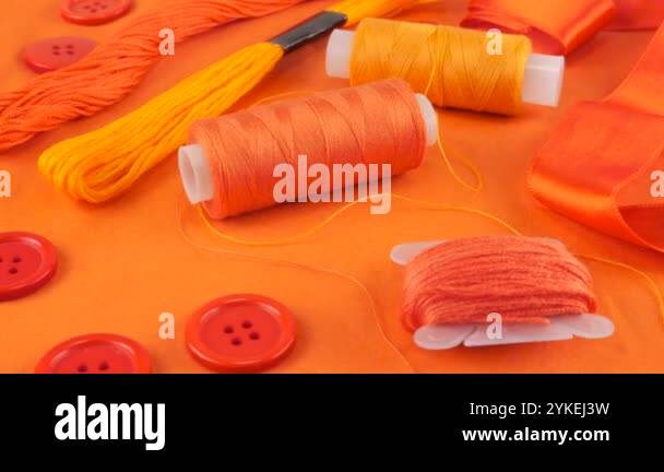 Close-up view of tufts orange cotton fabric, buttons and spools of ...