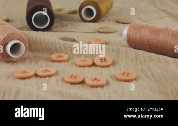 Thin beige cotton jersey, buttons and spools of threads in different ...