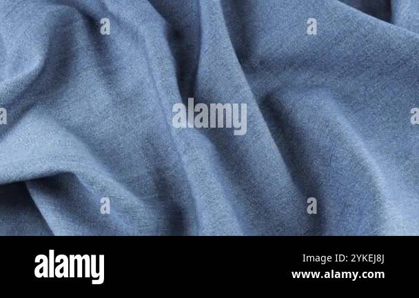 Soft folds of gray-blue denim fabric of a muted shade rotate on the ...