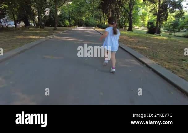 Little girl running outside in the park. Playing chase with his father ...