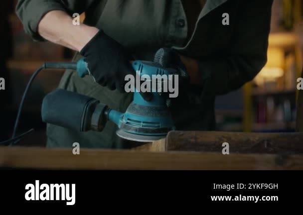 Tilt shot of concentrated middle-aged female carpenter in overall and ...