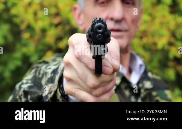 Man with black revolver in hand looks at the camera. Man with black gun ...