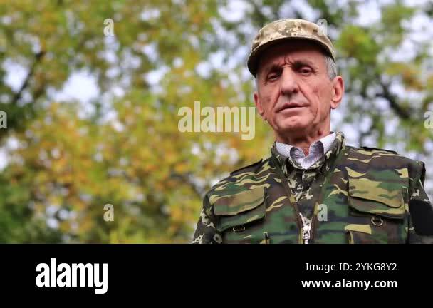 Retired officer in military uniform at shooting range. Senior man holds ...
