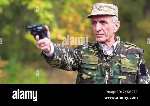 Retired officer in military uniform shoots a revolver. Man with black ...