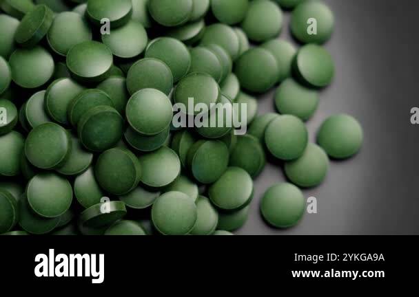Green spirulina algae tablets on a minimalist plate. Plant-based ...