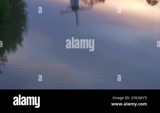 A Dutch windmill stands tall in the sky, framed by a stunning sunset ...