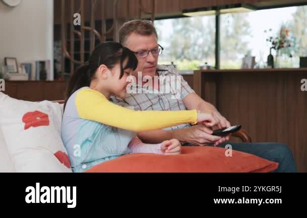 Grandfather and granddaughter watch interesting entertainment media on TV. Young generation ...