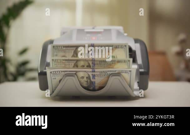 A cash counting machine processing a stack of hundred-dollar bills in a ...