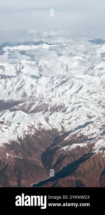 Vertical Above the peaks with clouds, capped Alps with rugged mountain peaks extending across ...