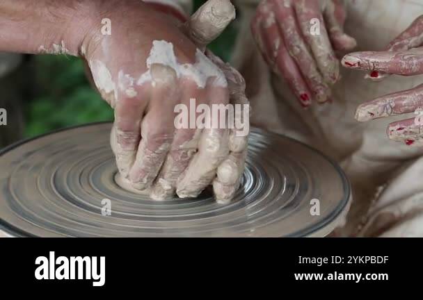 Man and woman makes a pot on pottery wheel. Hands of a potter and his ...
