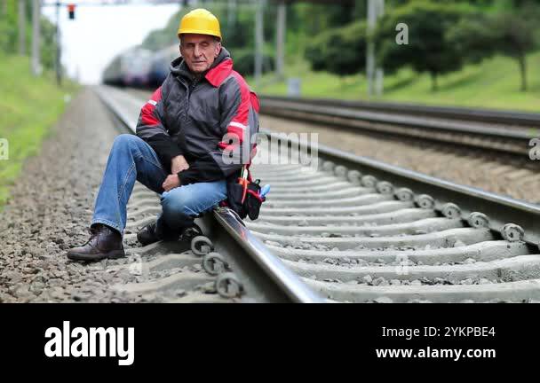 Railway worker sits on railway line. Train rides on the railroad ...