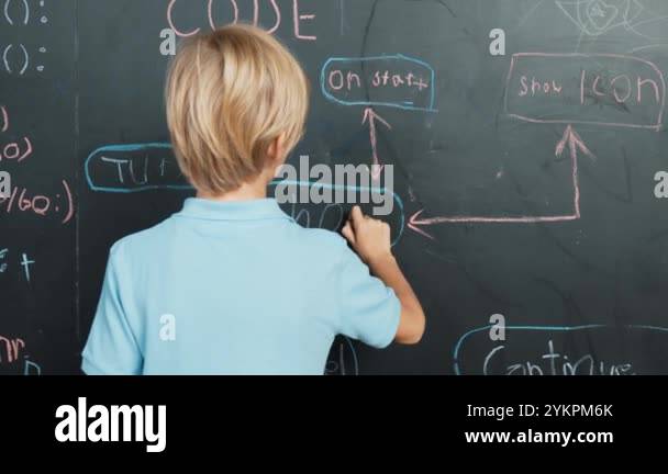 Back view of smart boy writing engineering prompt on blackboard while ...