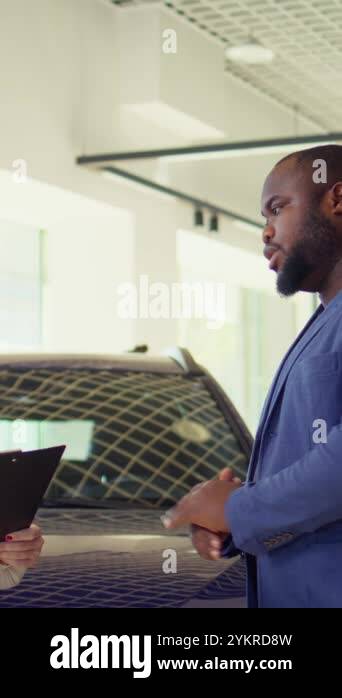 Vertical video Saleswoman in car dealership signing contract with man ...