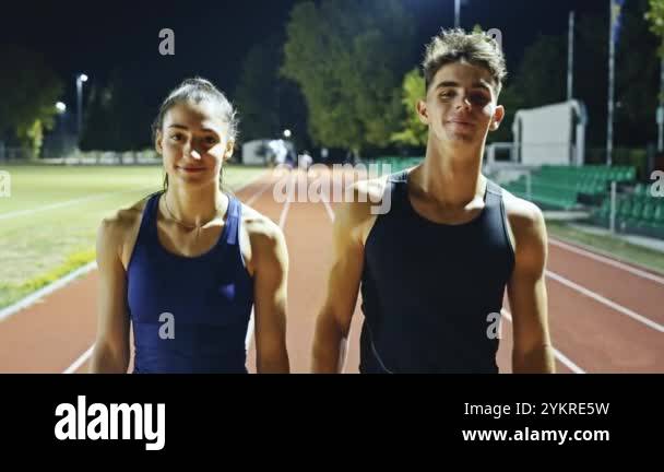 The sporty athletics couple is done jogging around the stadium. They ...