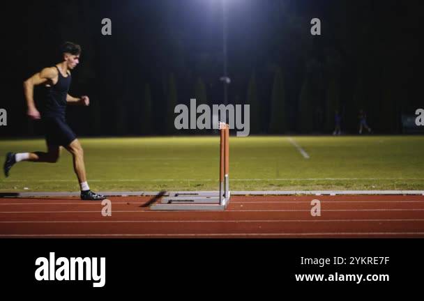 Strong Male Athlete is Running Towards an Obstacle, Hurdling, Jumping ...