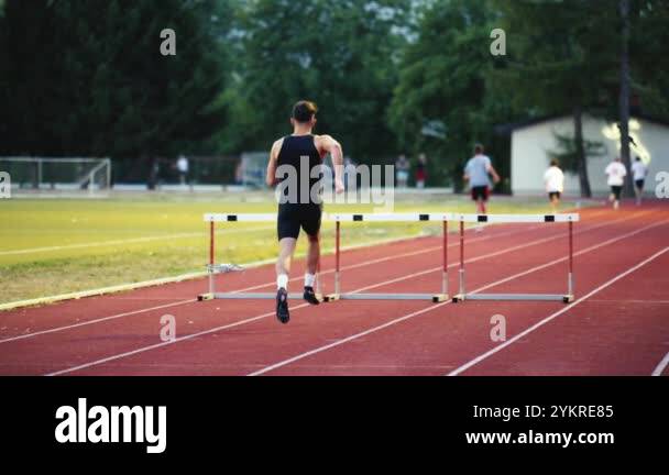 Strong Male Athlete is Running Towards an Obstacle, Hurdling, Jumping ...