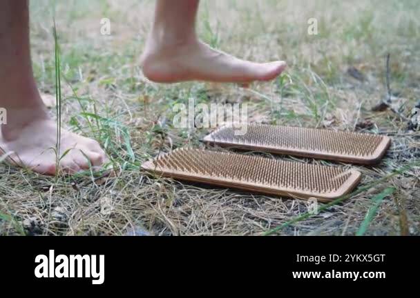 Barefoot man steps on a wooden spiky acupressure board in nature ...
