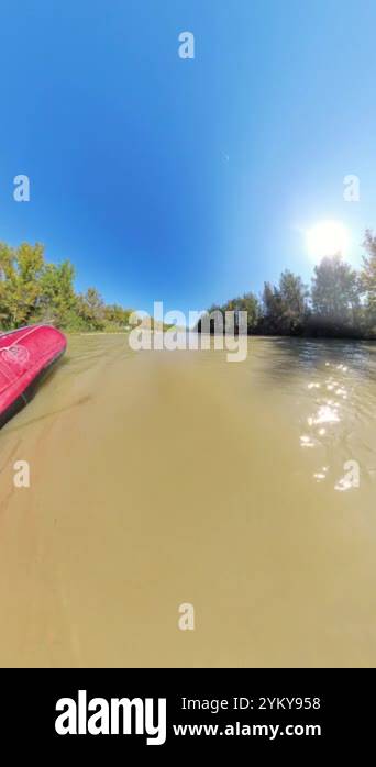 Vertical video. A wide view from the front of a rafting boat on a calm ...