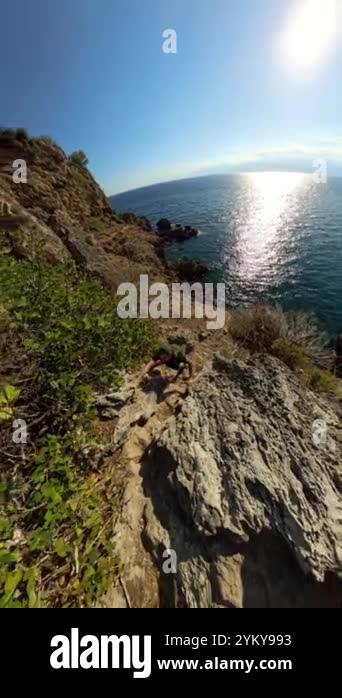 Vertical video. A steep coastal climb with a hiker scaling a cliffside ...