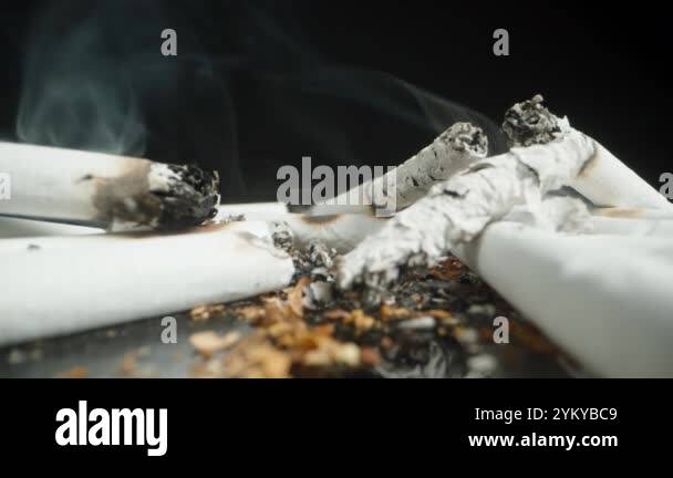 A dolly zoom shot of several burnt and crumpled cigarette butts on a ...