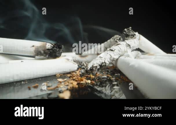 A wide shot of multiple burnt cigarettes and ashes scattered on a ...