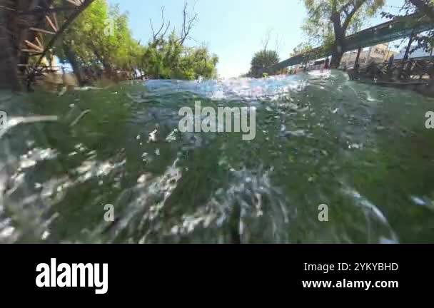 The camera plunges into a fast-moving river, capturing water breaking ...
