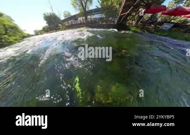 Panorama. A fast-flowing river surrounded by greenery and a wooden ...