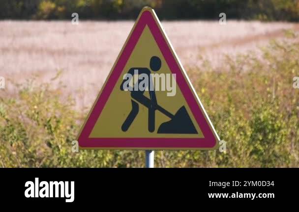 Roadworks red triangle sign with figure digging Stock Videos & Footage ...