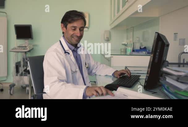 Mature GP sit at desk using computer accessing electronic health ...