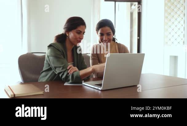 Happy busy Latin female coworkers sharing laptop, working at computer ...