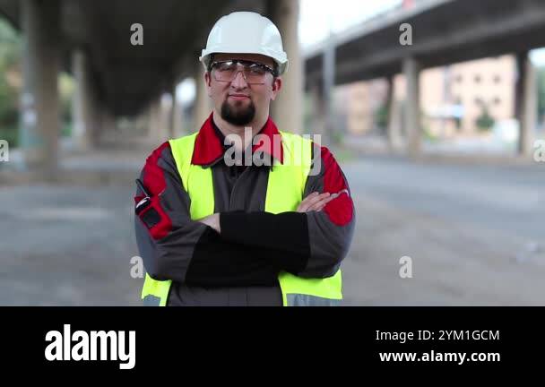 Worker stands under overpass and looks at the camera. Civil engineer in ...
