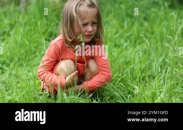 Little girl in red dress crying, because she got burnt with nettle ...