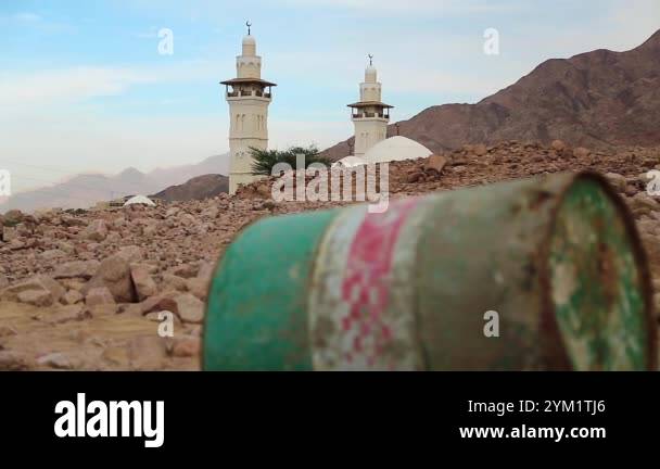 Iron barrel lies on the stony ground in defocus, mosque with two ...