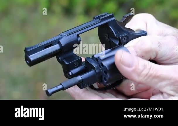 Man turns cylinder of black revolver. Man with black gun, close up. Man ...