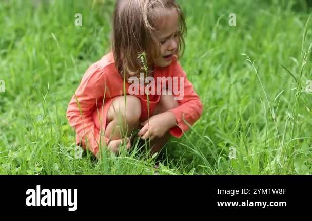 Little girl sits on green grass and crying. Girl in red dress crying ...